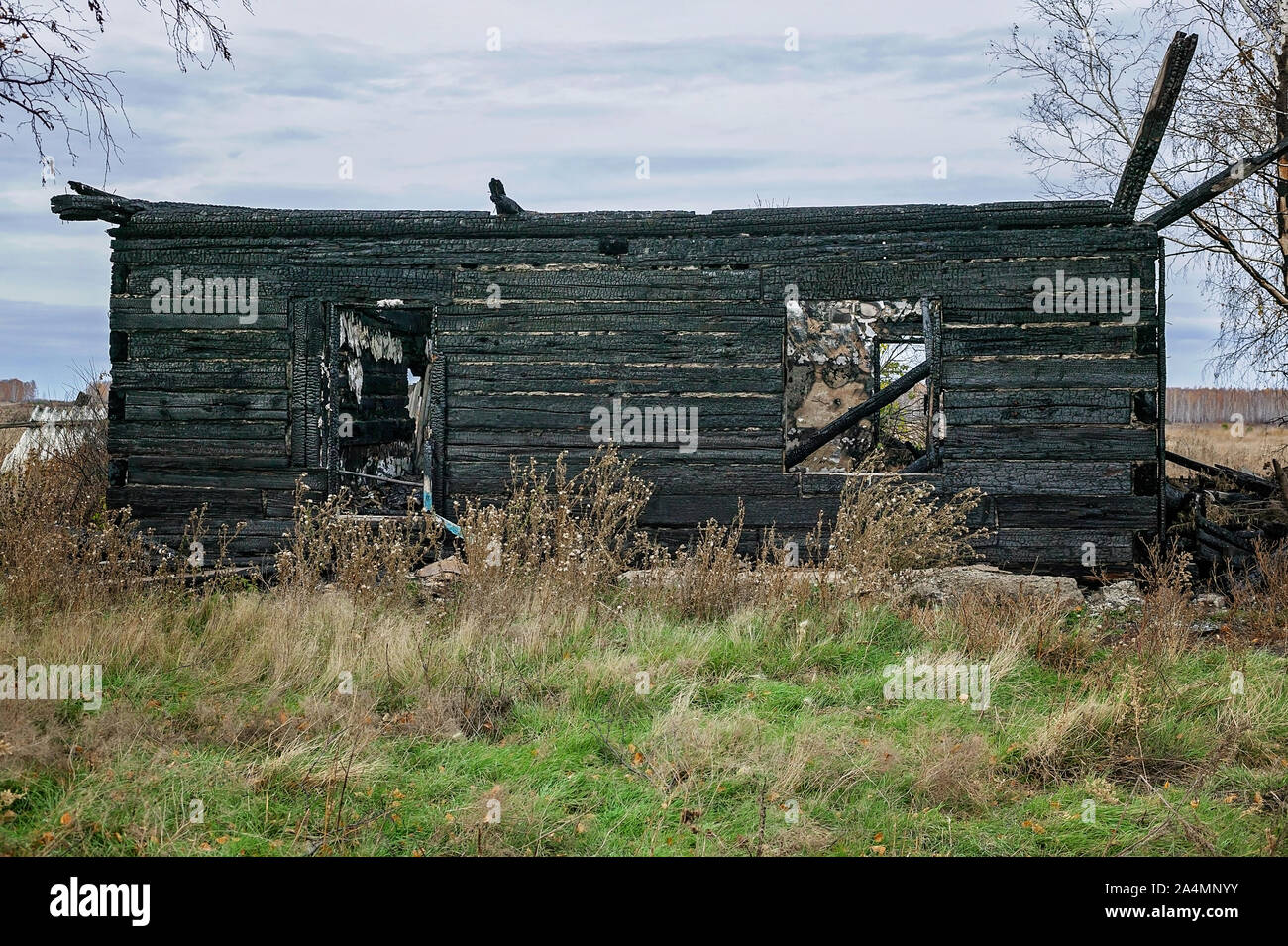 Burnt wooden house. Destroyed roof and windows, charred walls ...