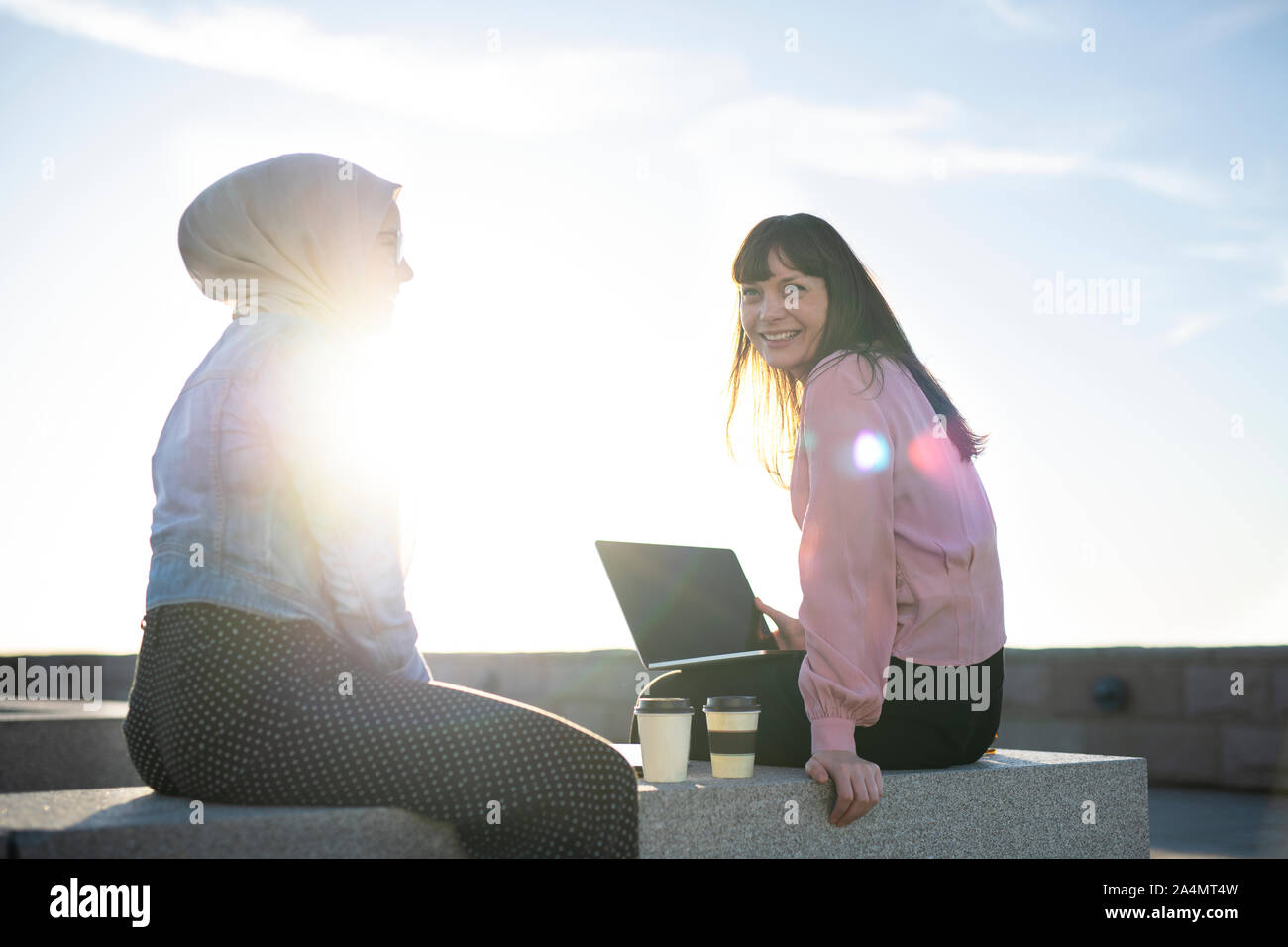Two friends sitting back back hi-res stock photography and images - Alamy