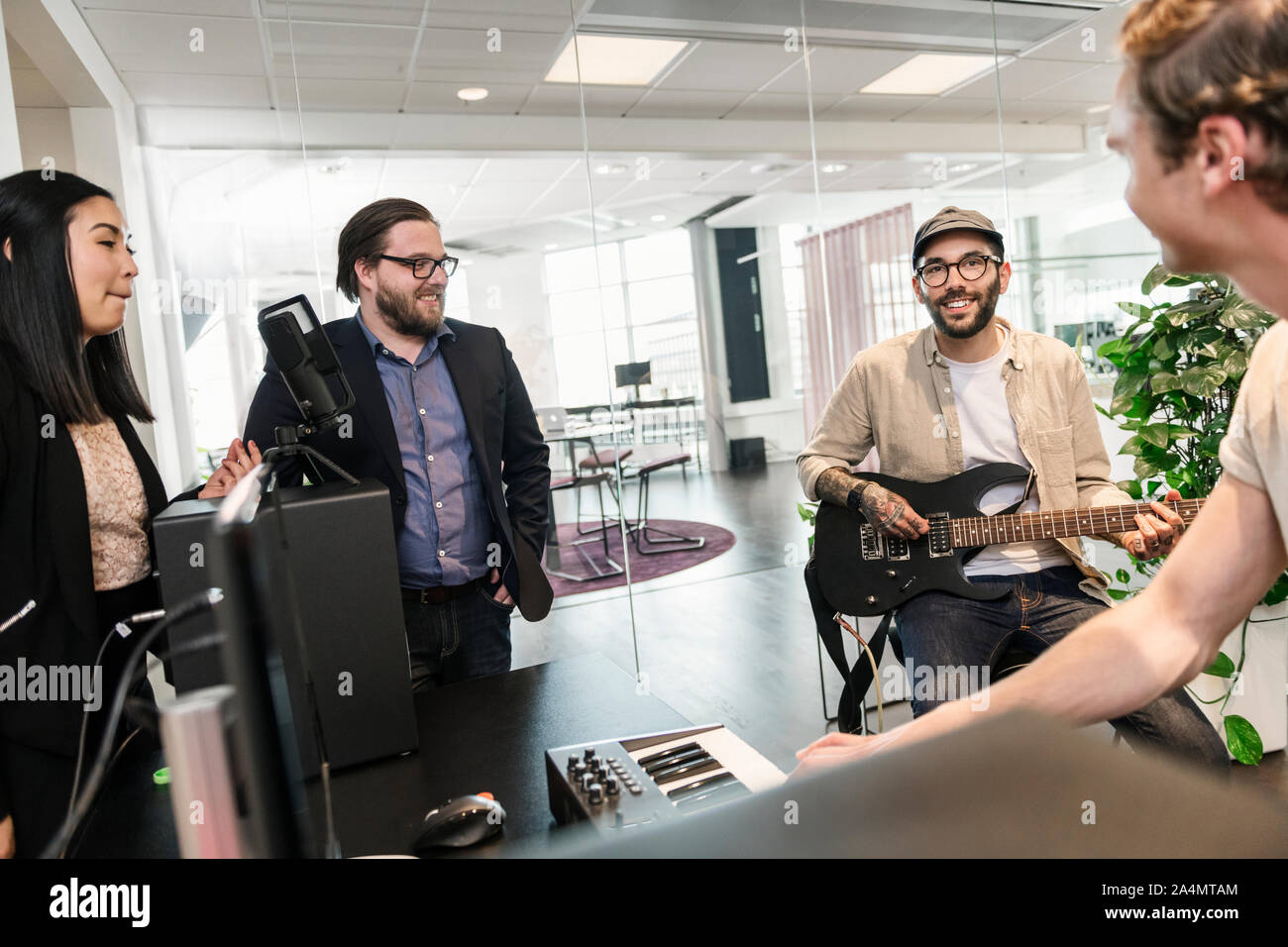 Young man playing guitar at office hi-res stock photography and images ...