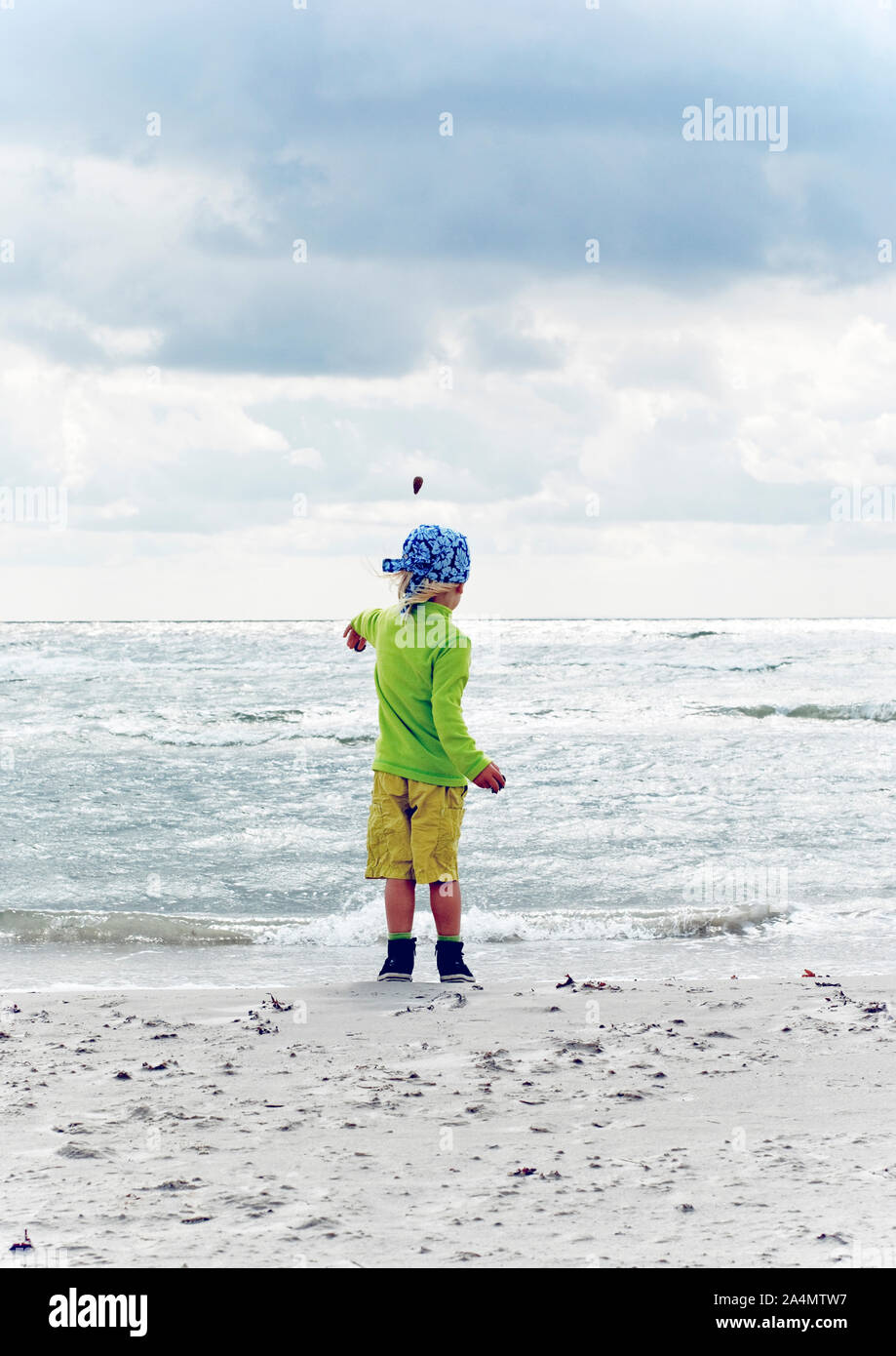 Child throwing stones on beach Stock Photo - Alamy