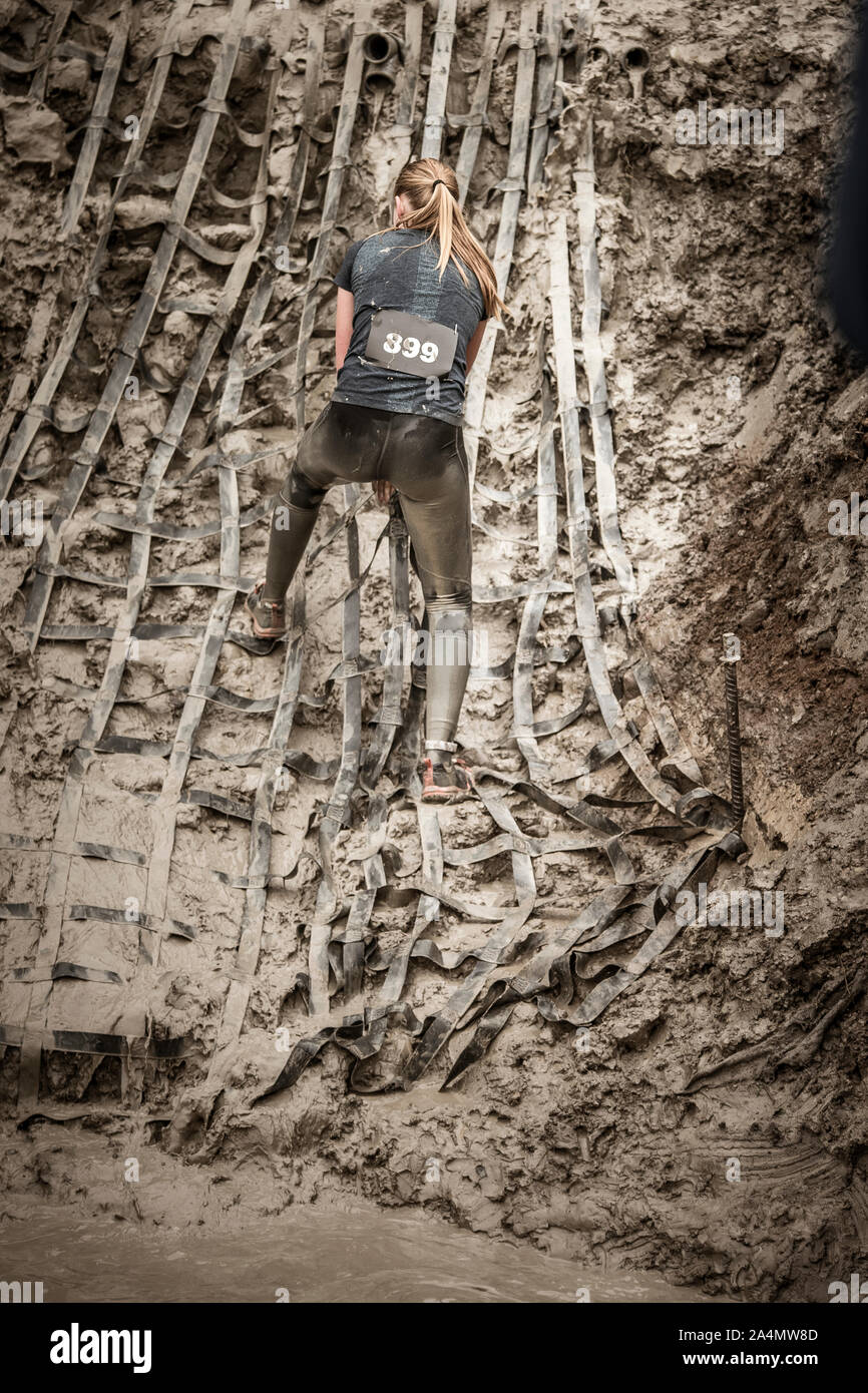 Woman climbing muddy cliff Stock Photo - Alamy