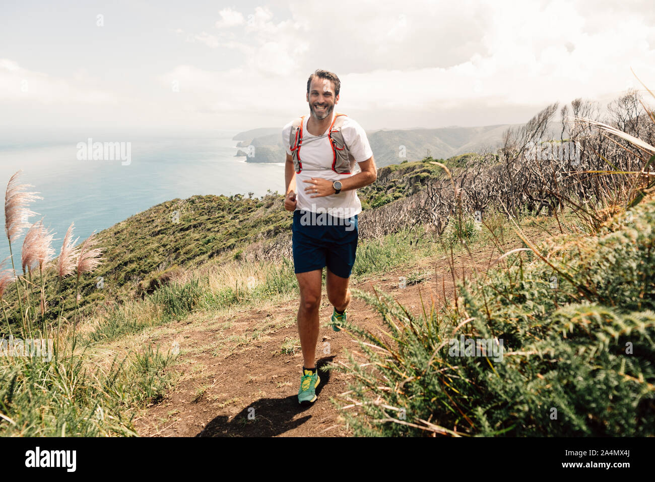 Smiling man running at coast Stock Photo - Alamy