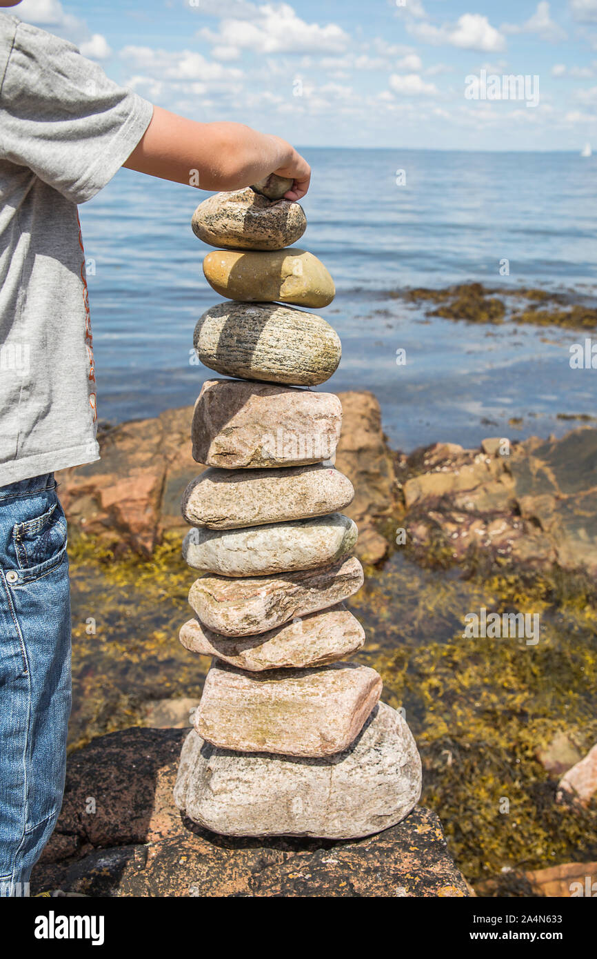 Boy stacking rocks Stock Photo - Alamy