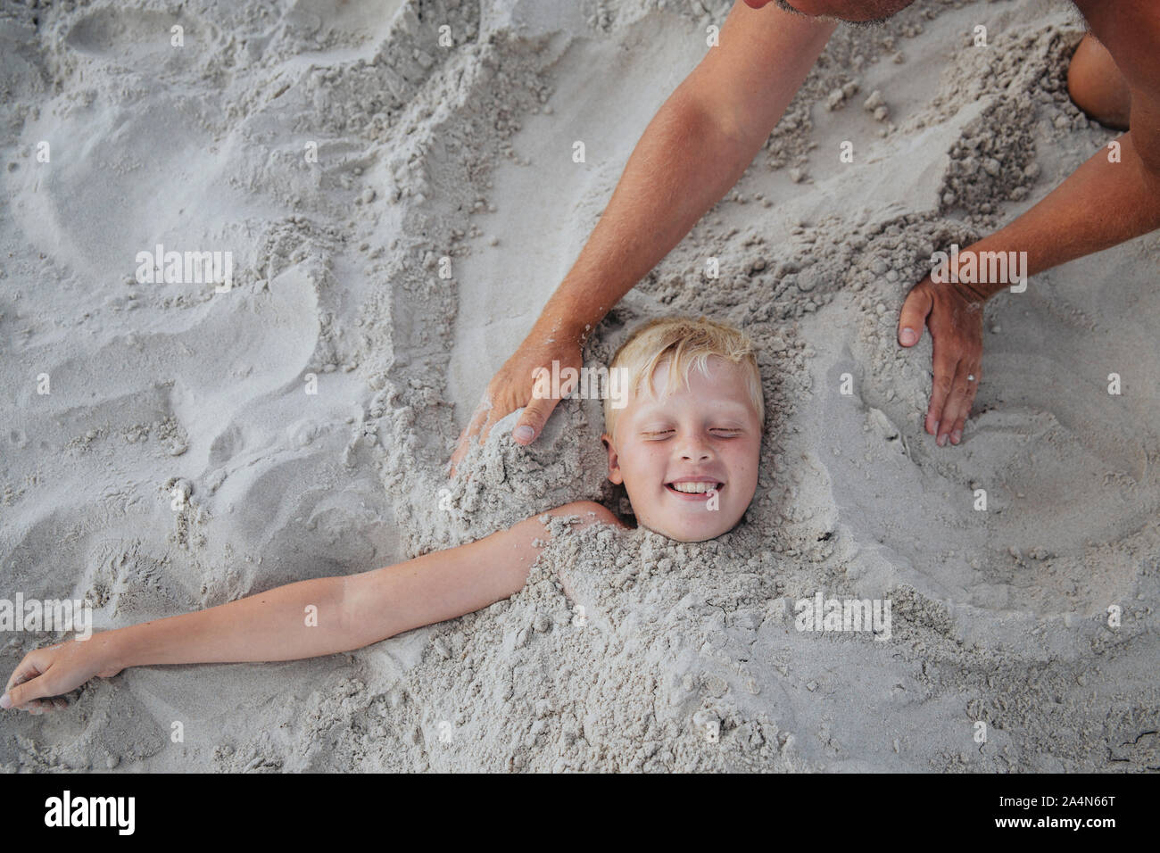 Boy buried in sand Stock Photo - Alamy