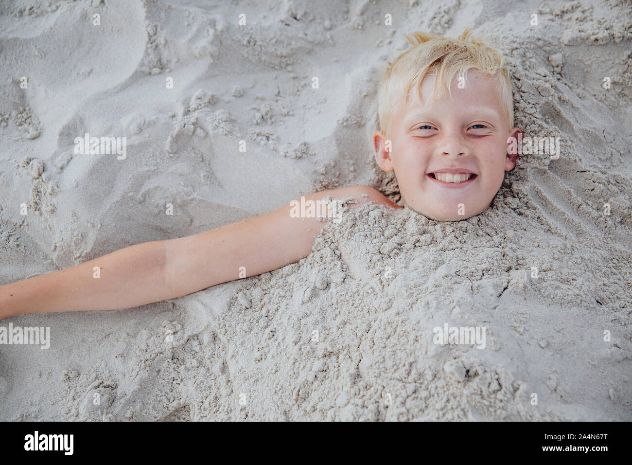 Boy buried in sand Stock Photo - Alamy