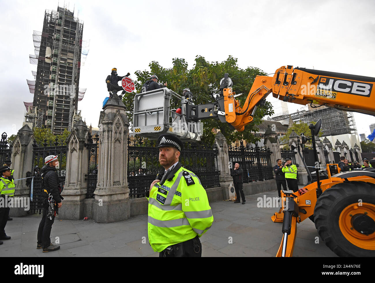 An Extinction Rebellion protester sits on fence pillar at the houses of ...