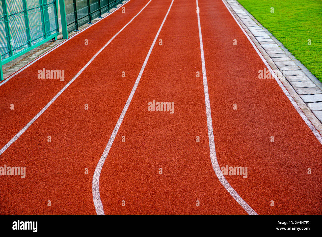 Red running track with white lines in outdoor sport stadium, side is a ...