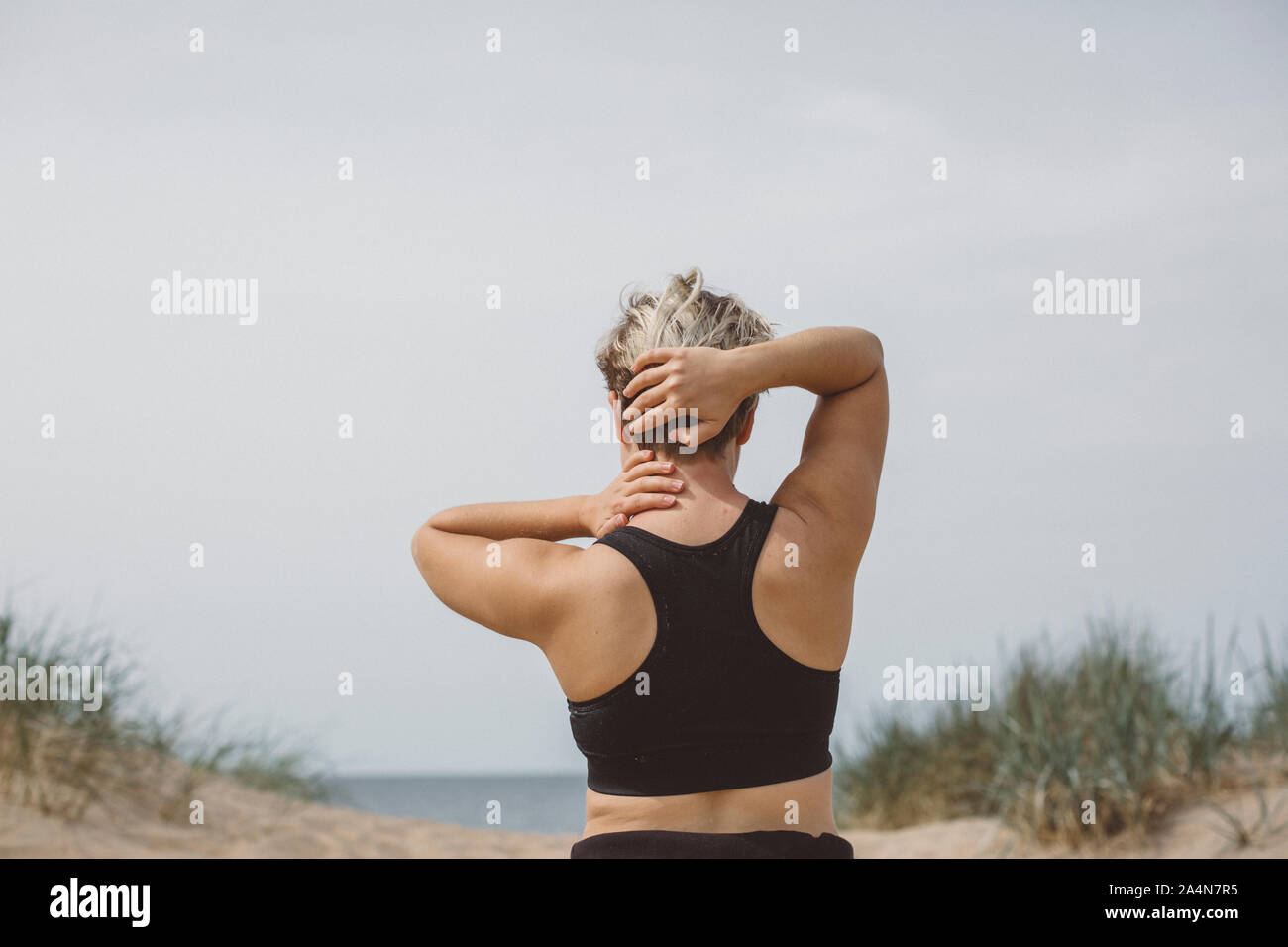 Woman with hands on neck Stock Photo - Alamy