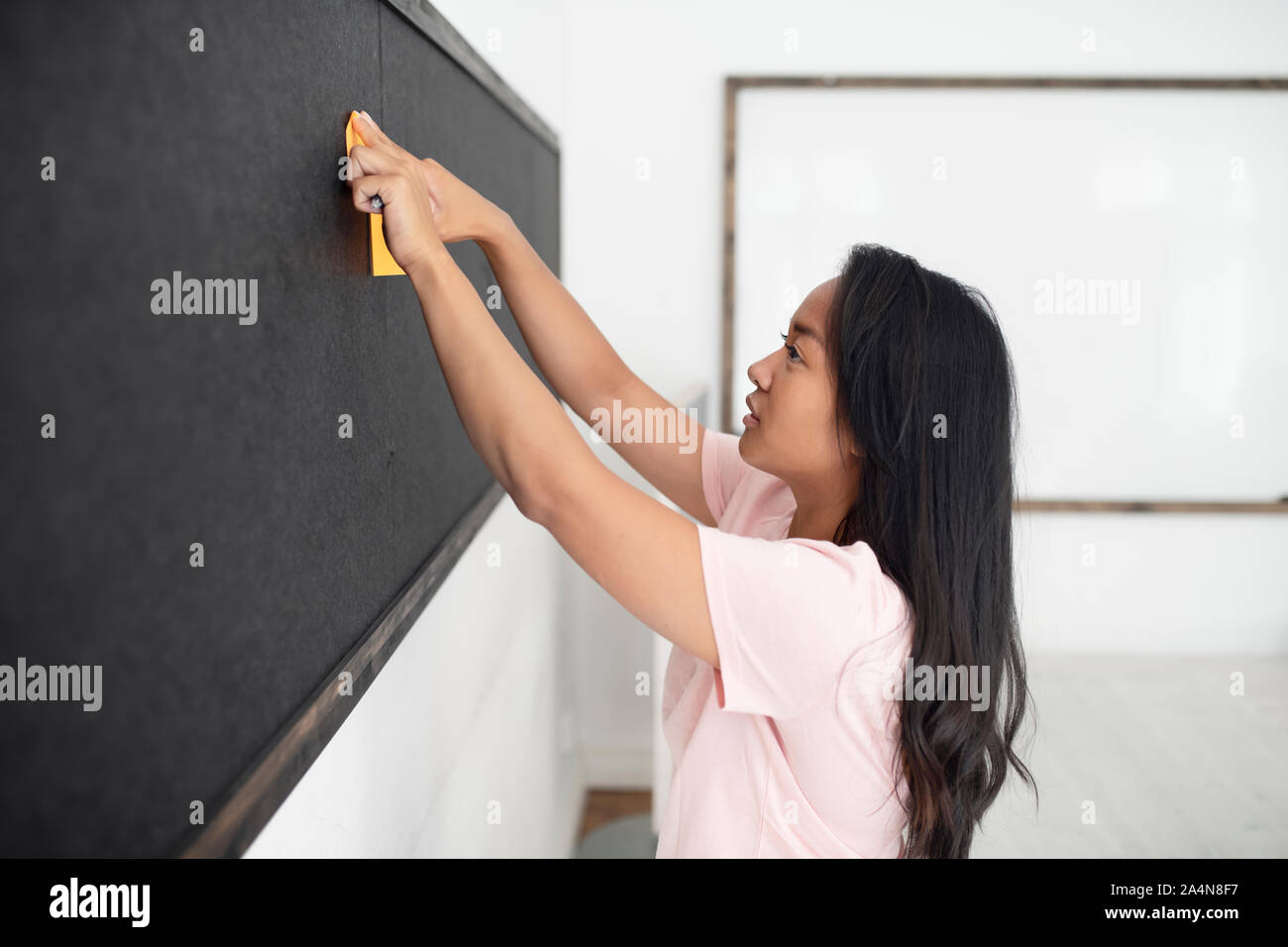 Woman putting post it on blackboard Stock Photo - Alamy
