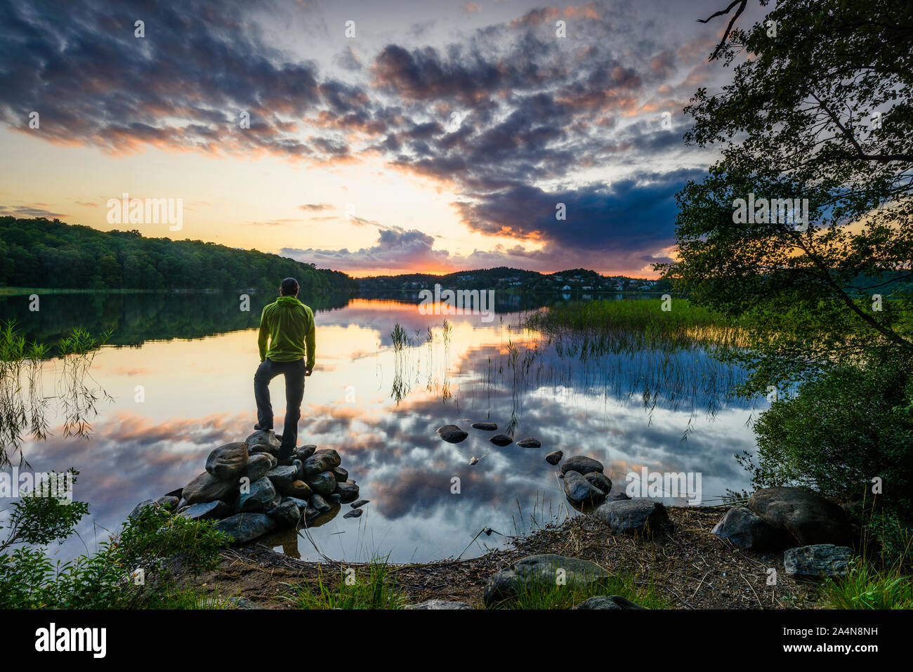 Man standing by lake at sunset Stock Photo - Alamy