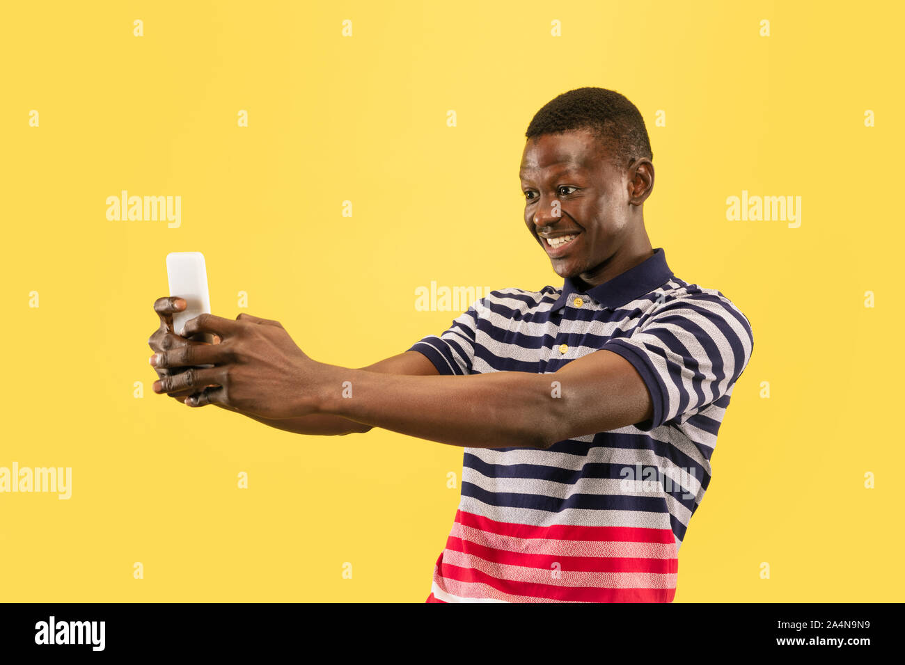 Let's tak a selfie. Young african-american man with smatphone isolated ...