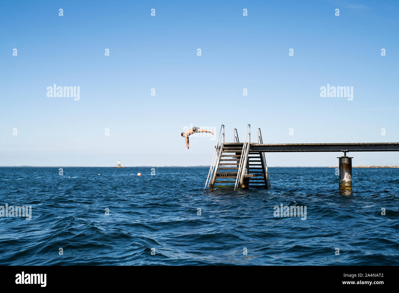Man jumping into sea from pier Stock Photo - Alamy
