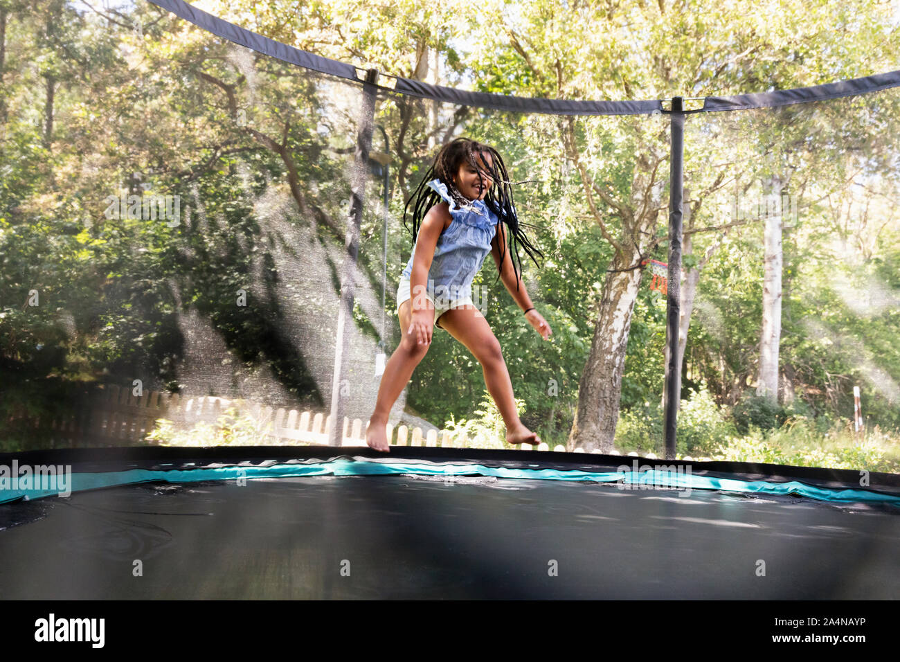 Girl jumping on trampoline Stock Photo - Alamy