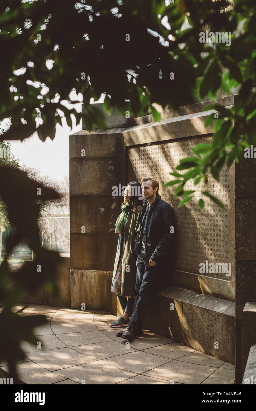 Young couple standing against wall Stock Photo - Alamy