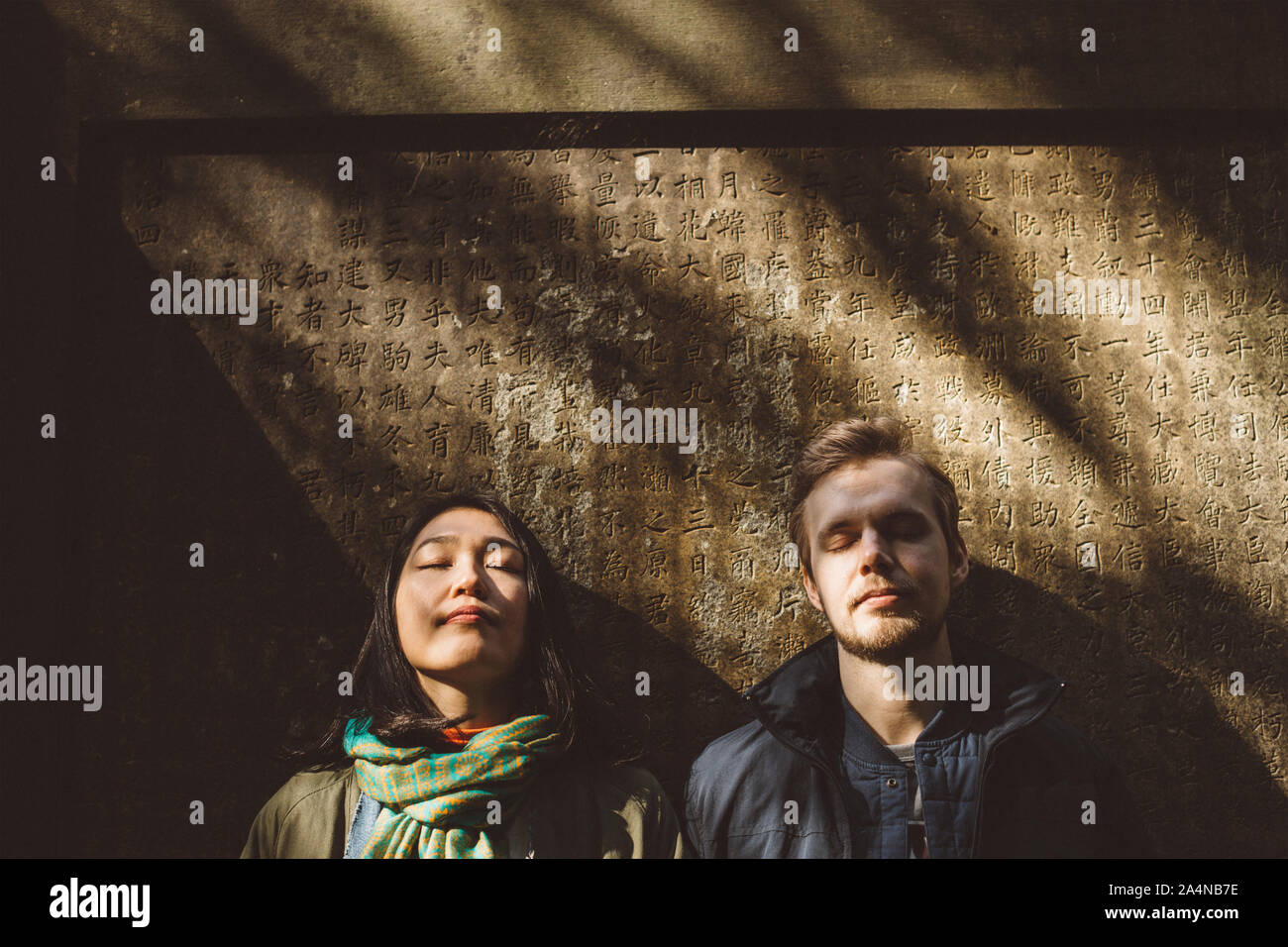 Young couple standing against wall Stock Photo - Alamy