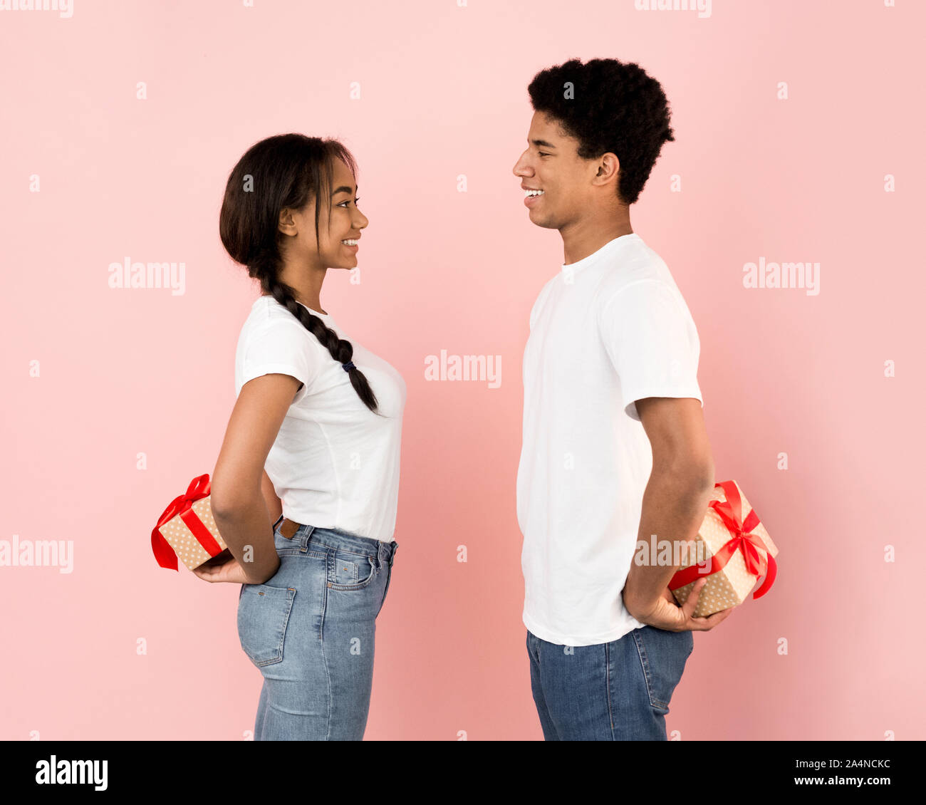 Cute couple holding present boxes behind their backs Stock Photo - Alamy