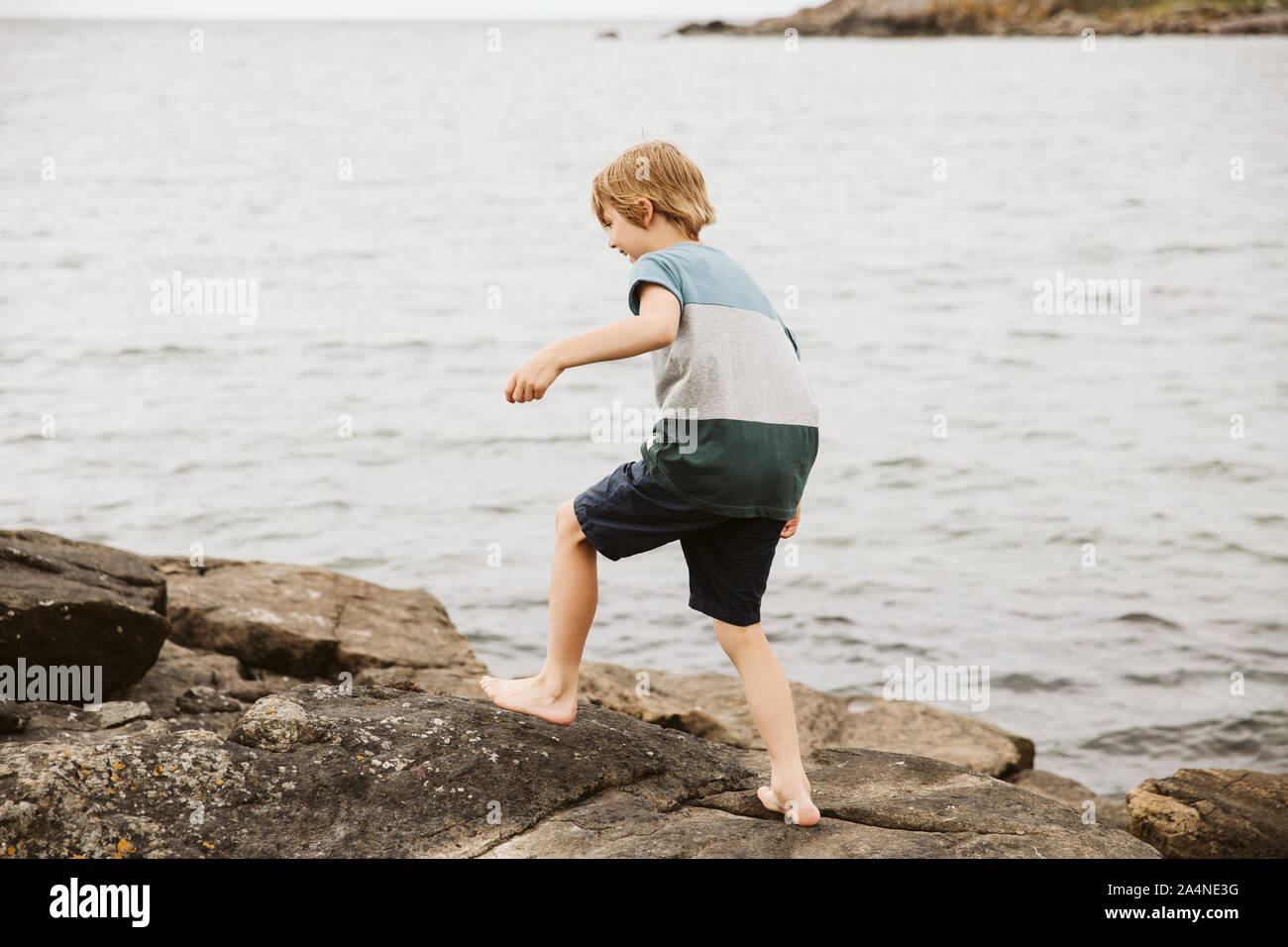 Boy walking on rocks at seaside Stock Photo - Alamy