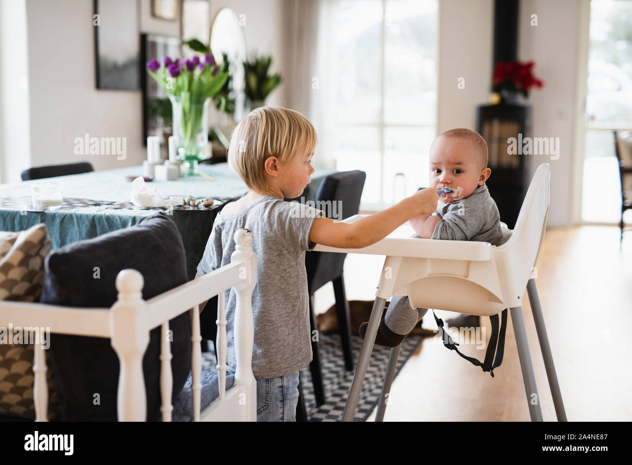 Boy feeding baby brother Stock Photo - Alamy