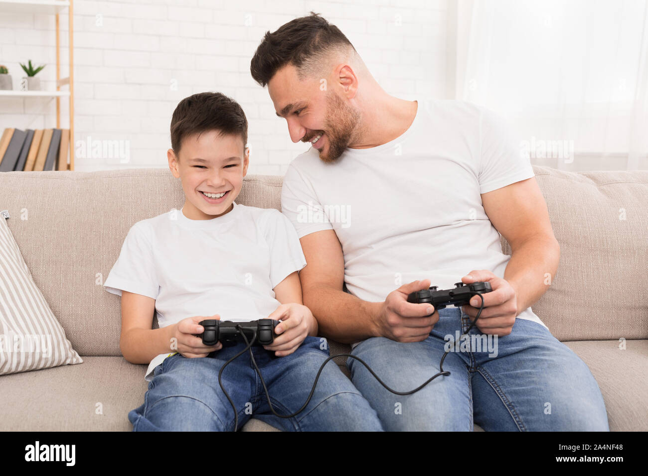 Dad and son with joysticks playing video games at home Stock Photo - Alamy