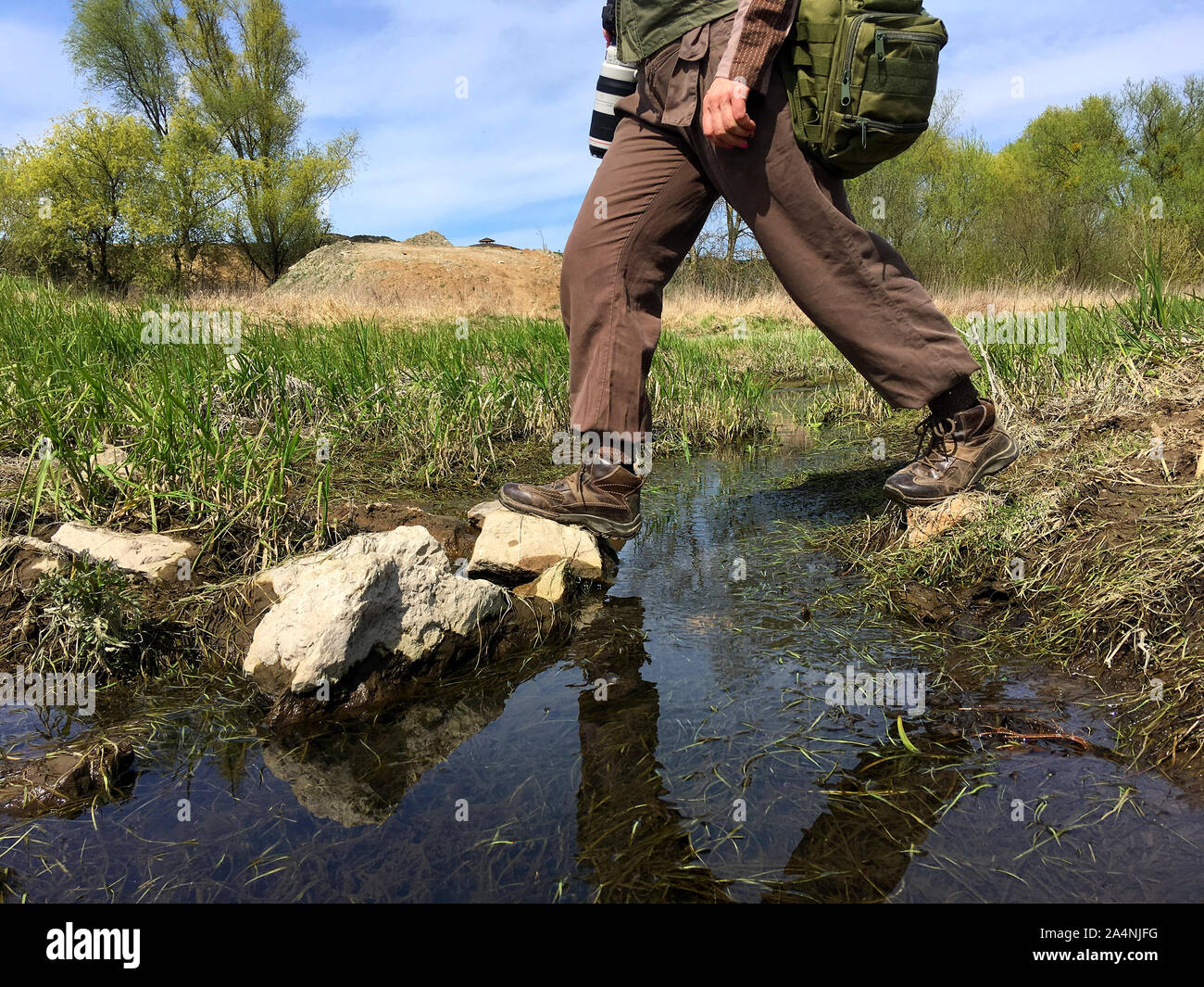 the legs of a wanderer on stones over a stream in the summer Stock ...