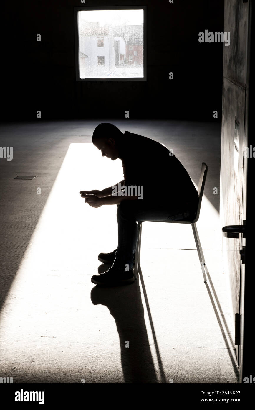 Light falls through a square window into a large, empty room; a man ...