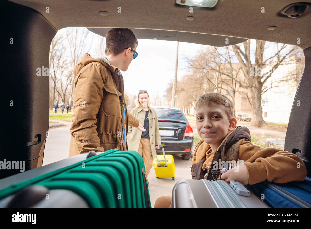 family with kid putting bag in car trunk Stock Photo - Alamy