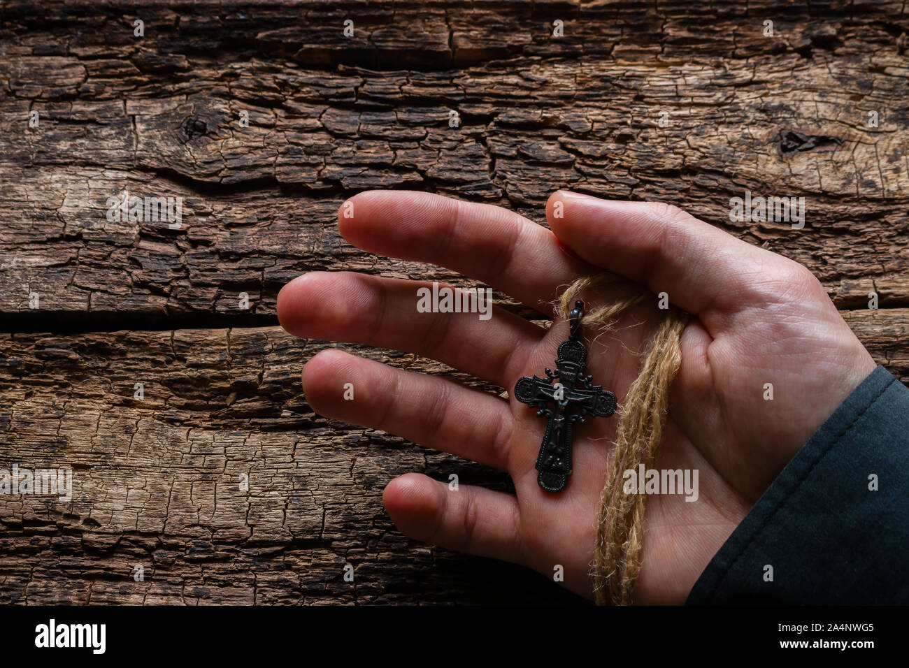 man holding a cross on a wooden background Stock Photo - Alamy