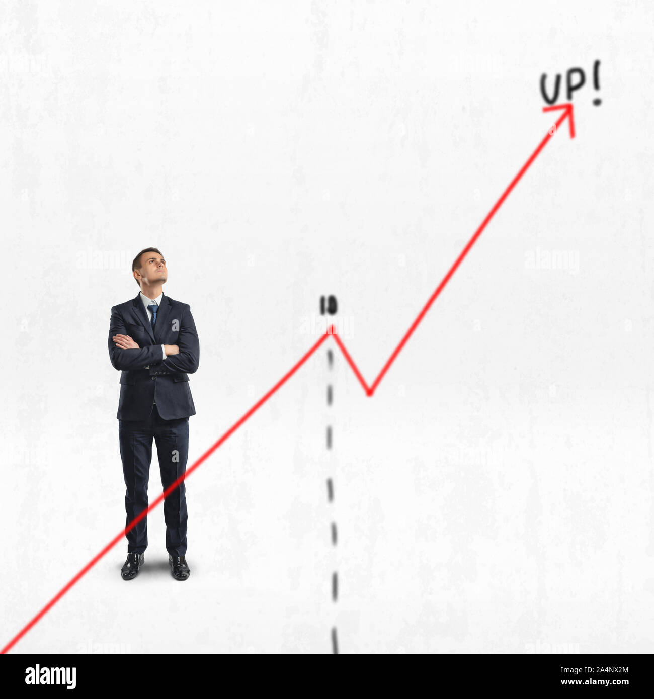 Businessman stands with folded arms looking upwards behind big rising ...