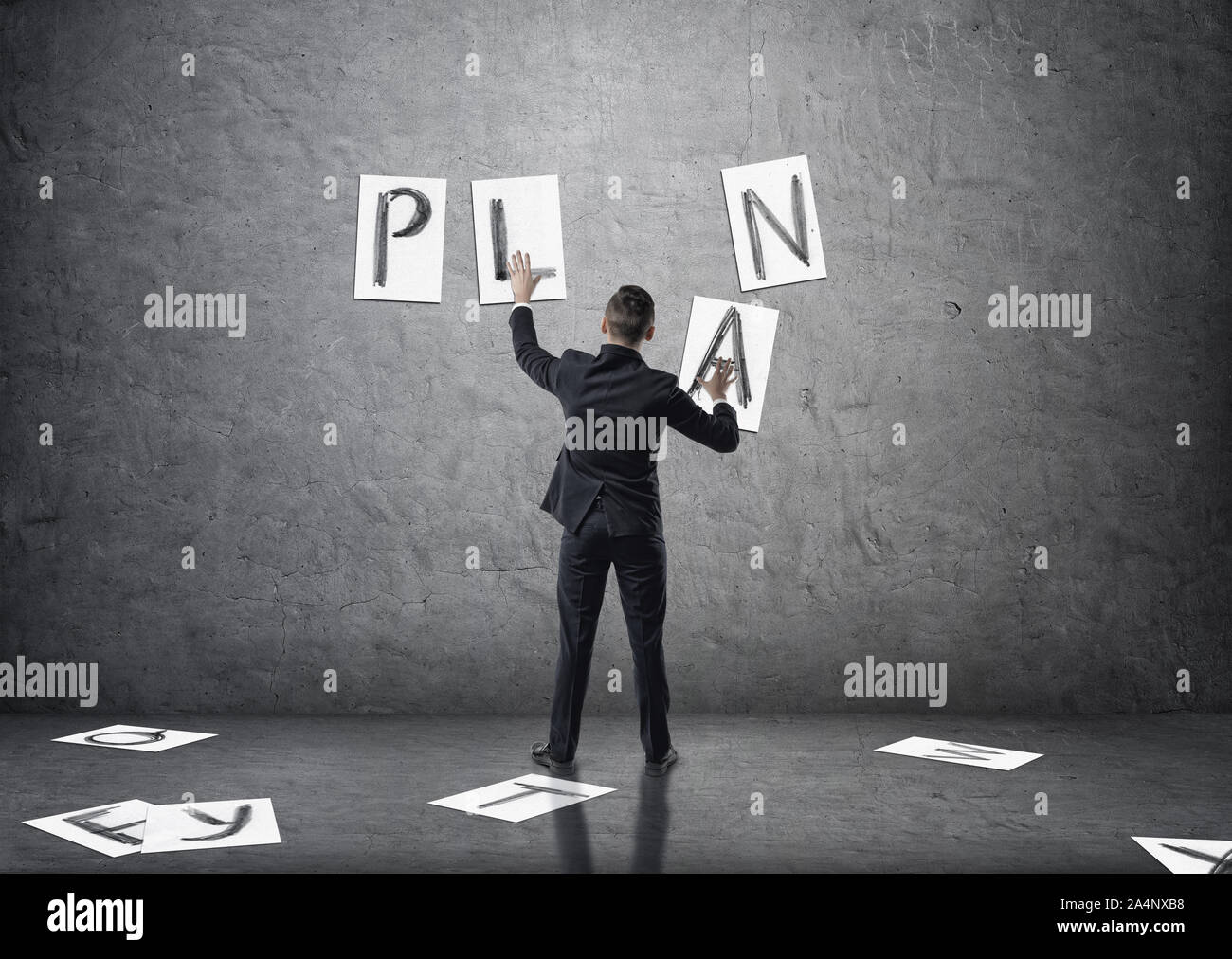 Businessman putting up posters with letters on concrete wall that form ...