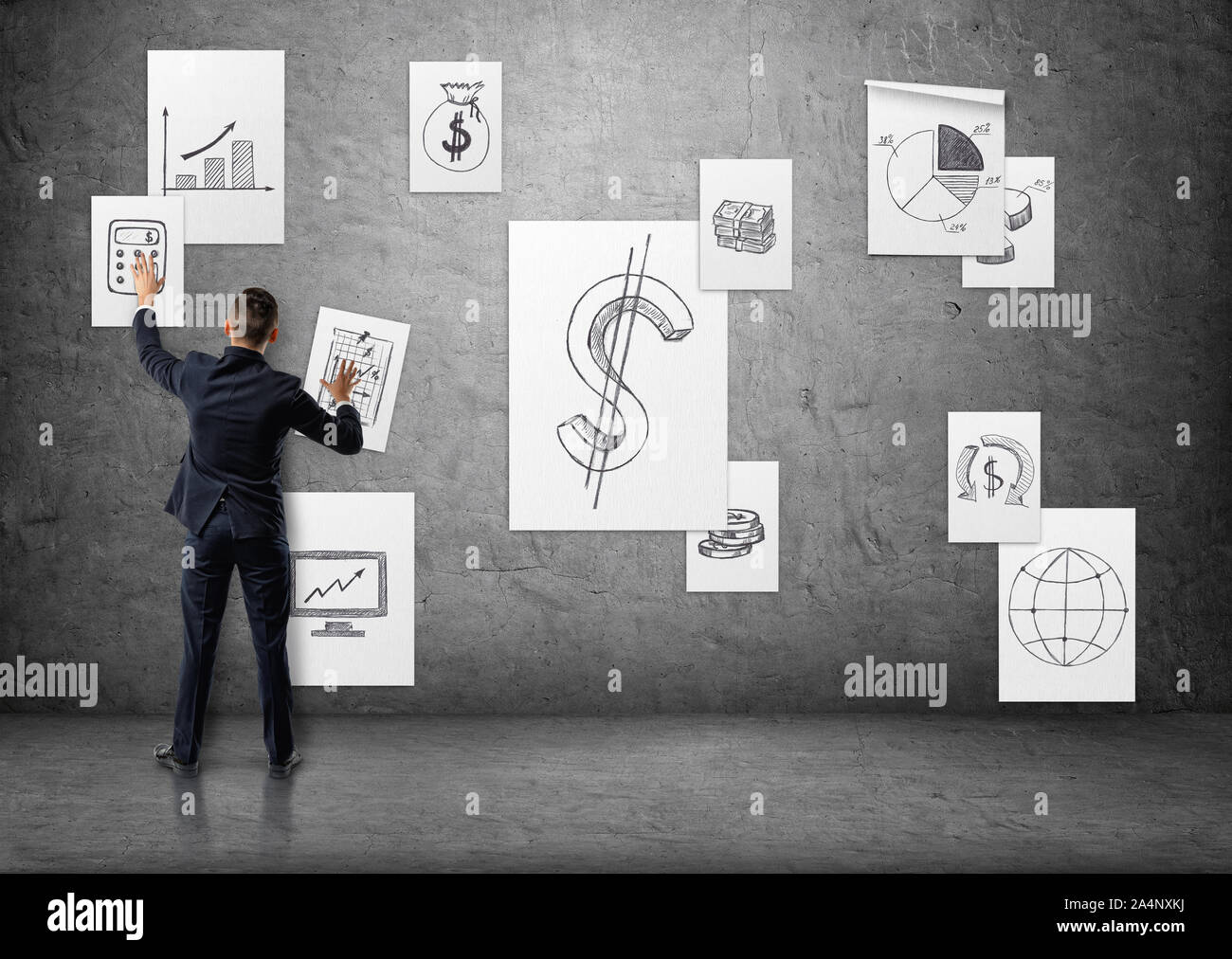 Businessman putting up business posters with sketches on concrete wall ...