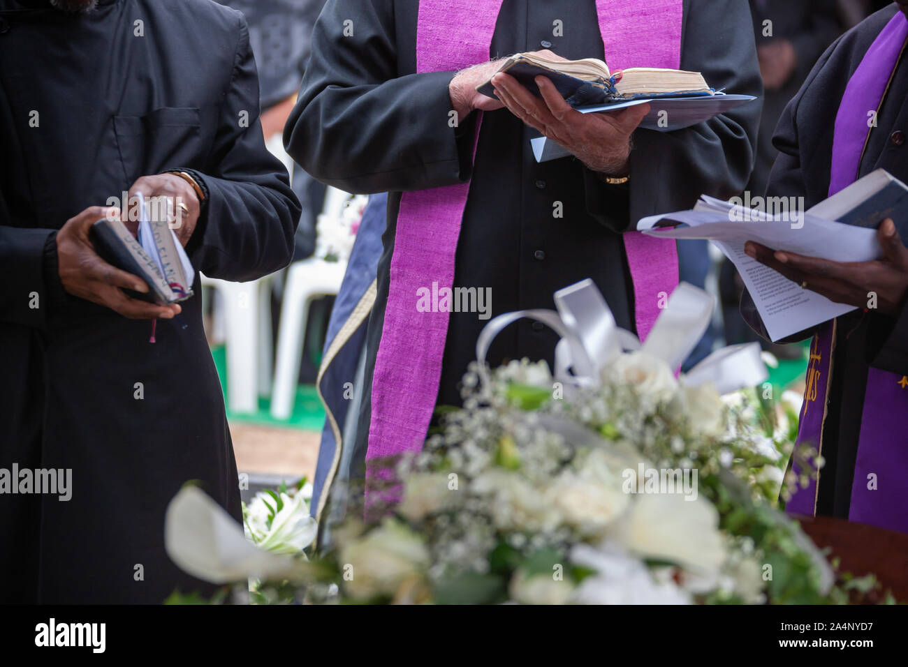 Three Anglican priests attending a funeral, next to the grave Stock ...