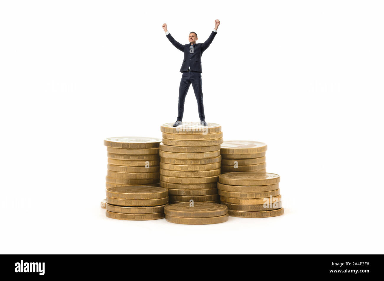 Businessman standing on stack of coins with his hands up in celebrating ...