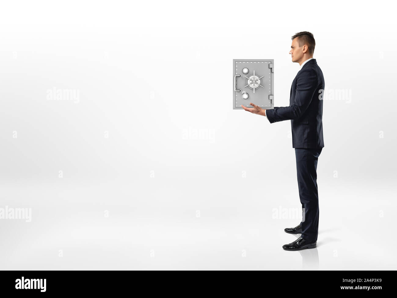 Businessman standing sideways and holding gray metal safety box in his ...
