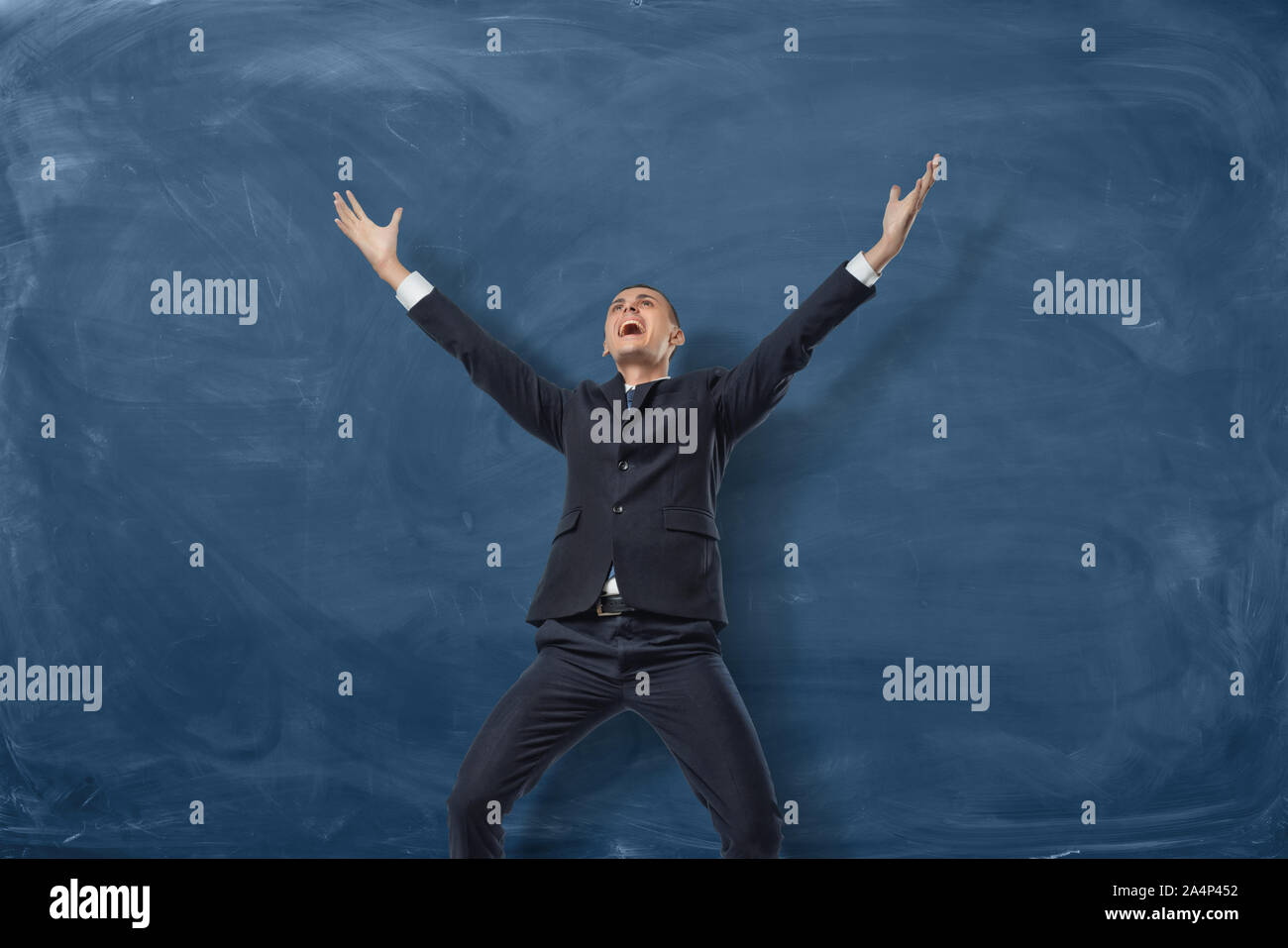 Businessman standing with splayed arms and shouting on the blue ...
