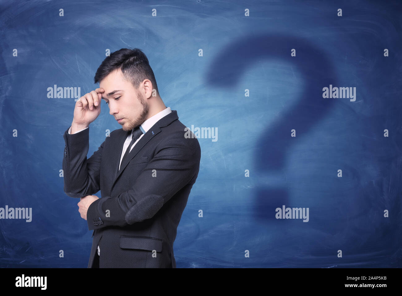 Thoughtful businessman on blue chalkboard background with a shadow ...