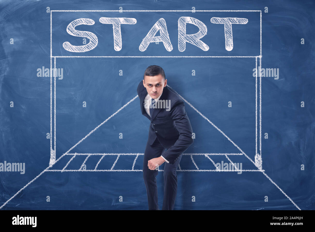 Businessman standing in running position on blue blackboard background ...