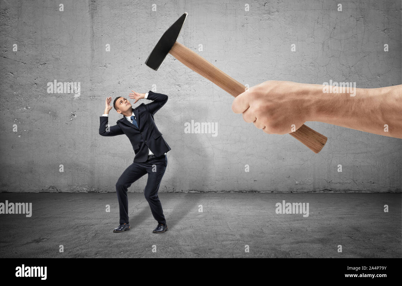 Scared businessman full-height in a desperate pose and a giant hand ...