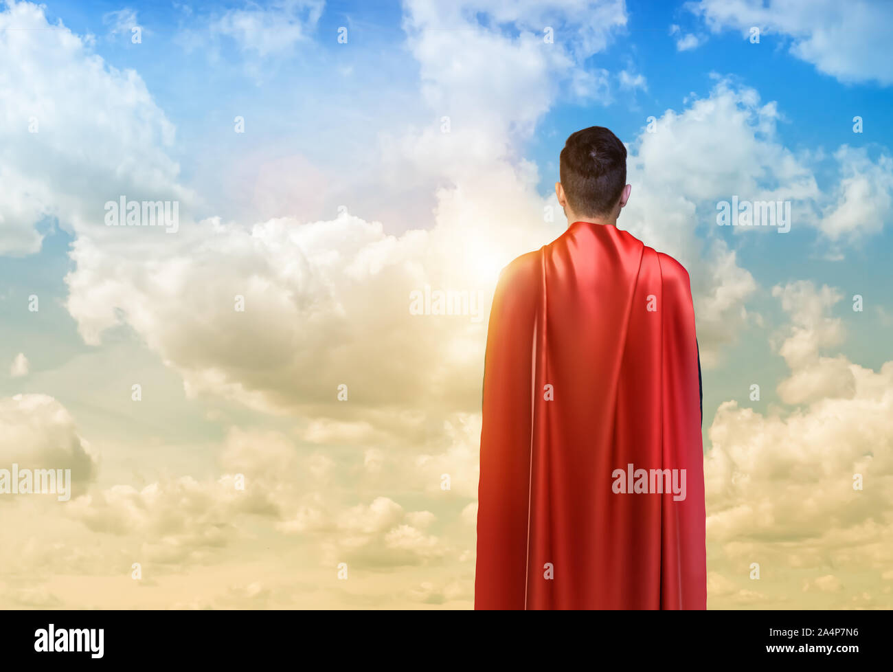 A businessman in super hero cape standing turned back on the sky ...