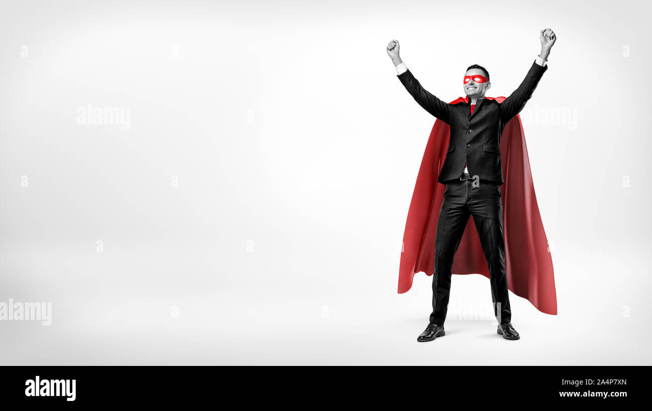 A happy businessman in a superhero red cape standing in victory pose on ...