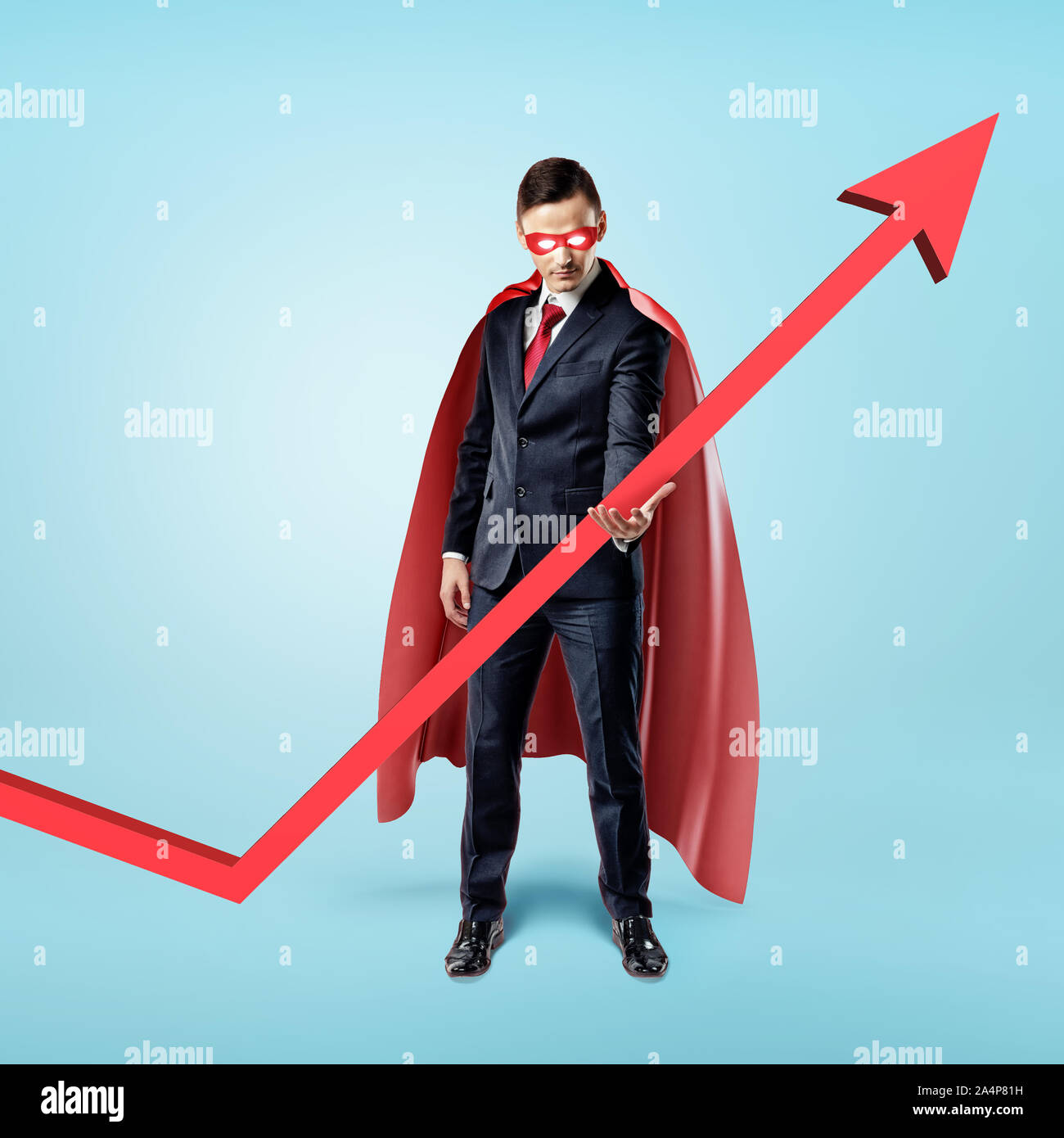 A businessman in a red flowing cape trying to keep the upward looking ...