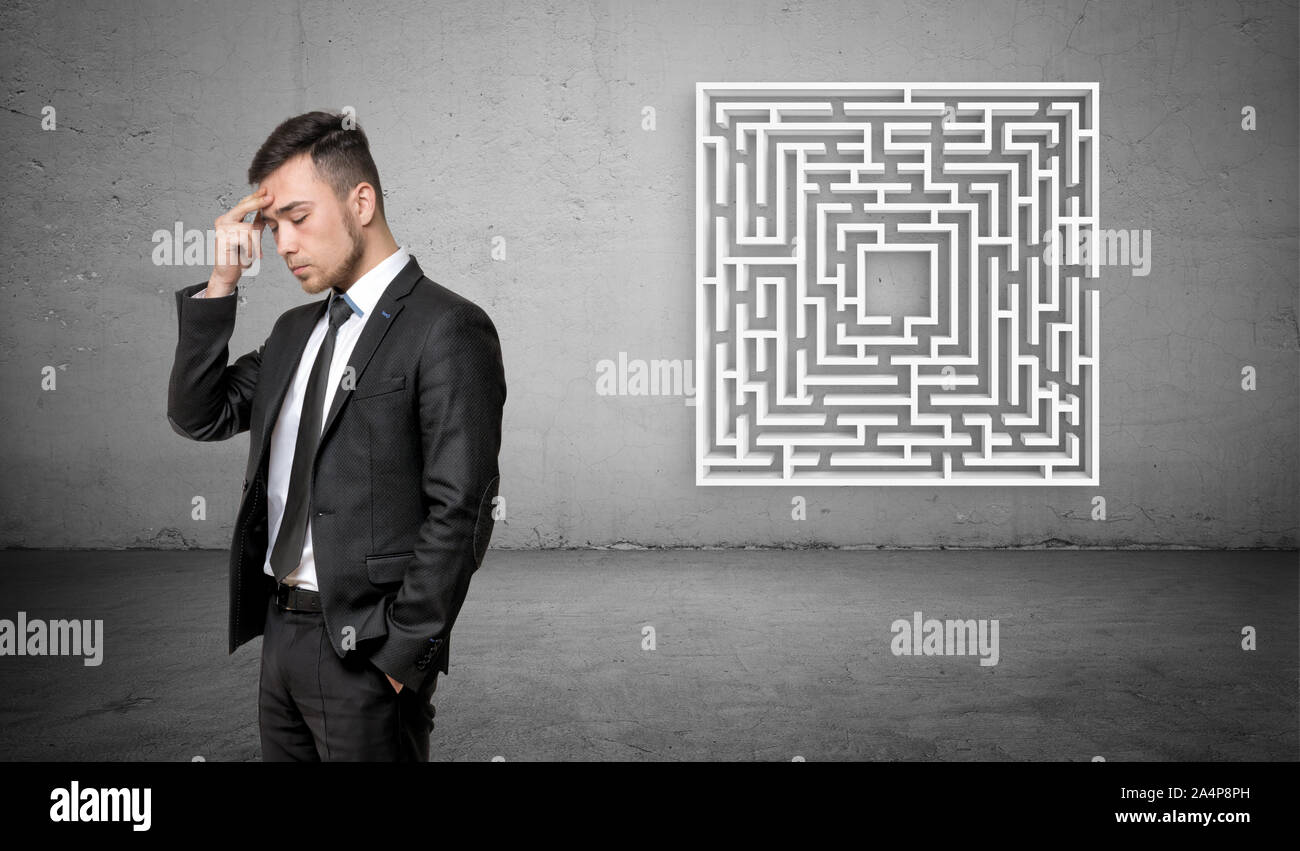A businessman in deep thought with a white maze on concrete background ...