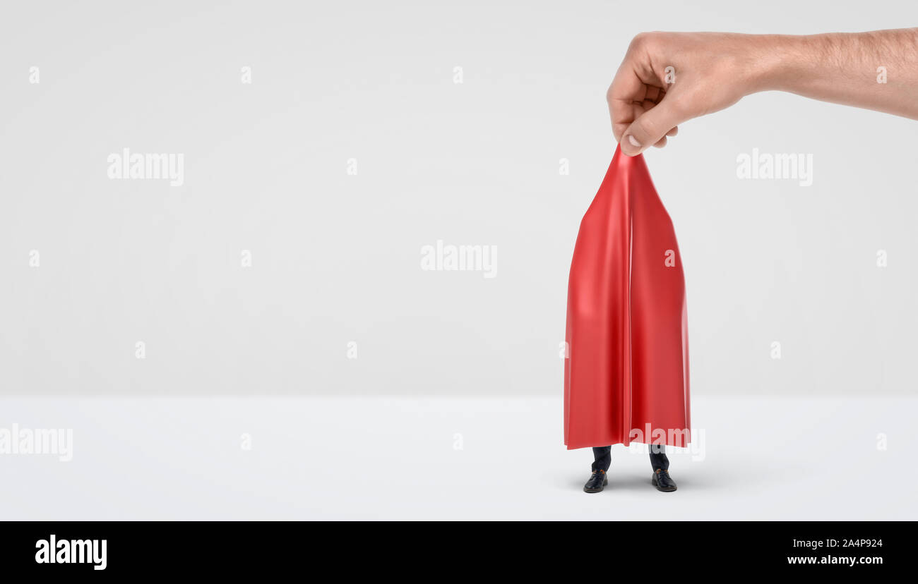 A giant hand taking off a red drapery from a hidden businessman on ...