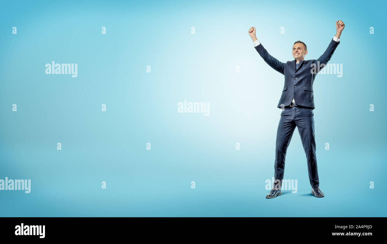 A happy smiling businessman on blue background standing with hands ...