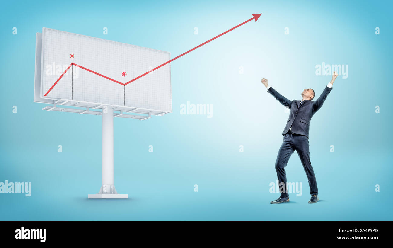 A happy businessman standing beside a large billboard with a red ...