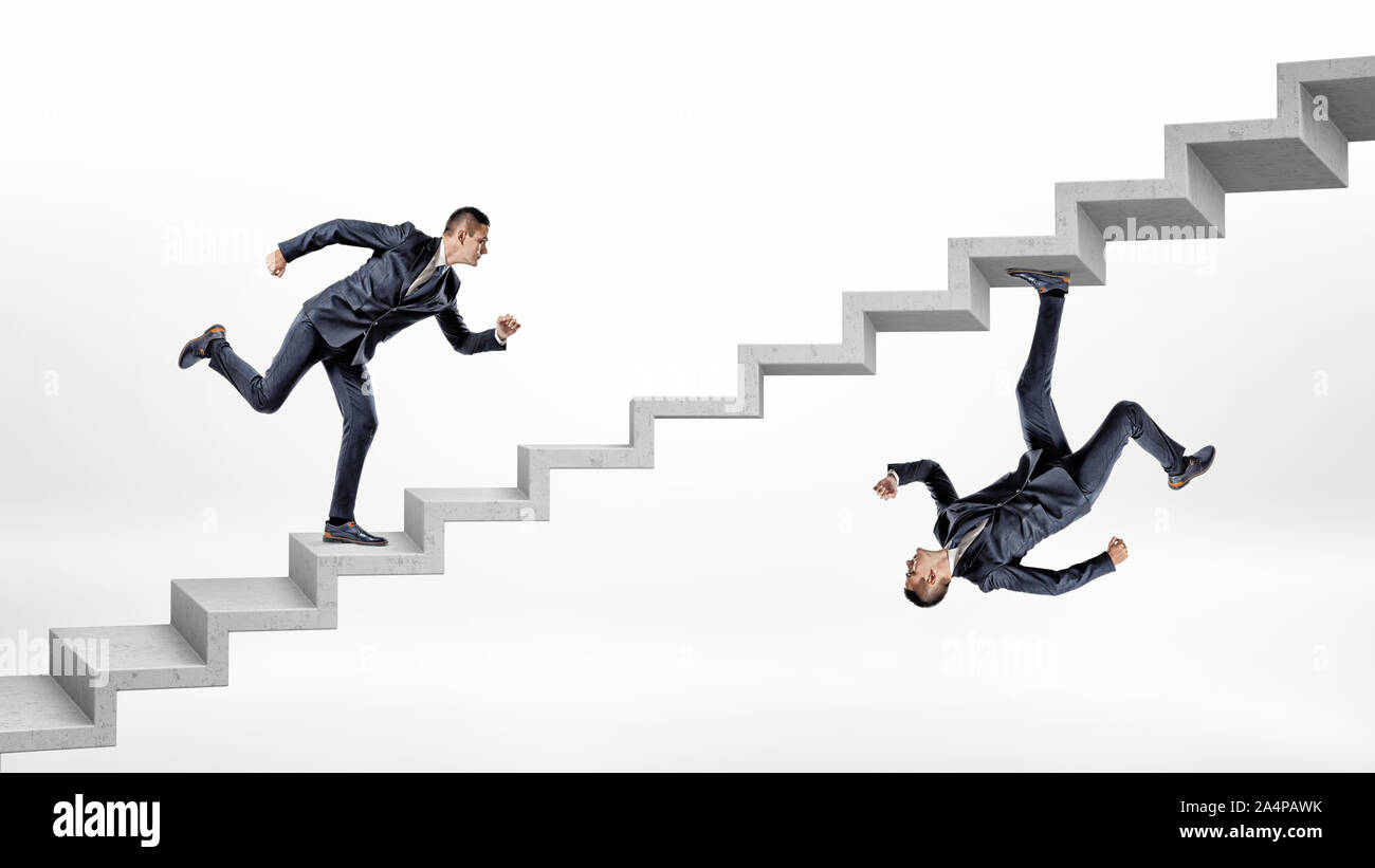Two businessmen running up concrete stairs in overturned reflected ...