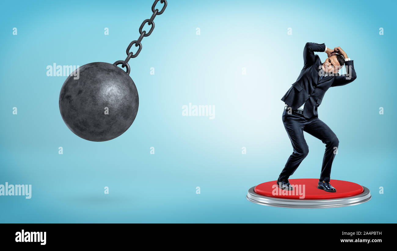 A scared cowering businessman stands on a huge push button and hides ...