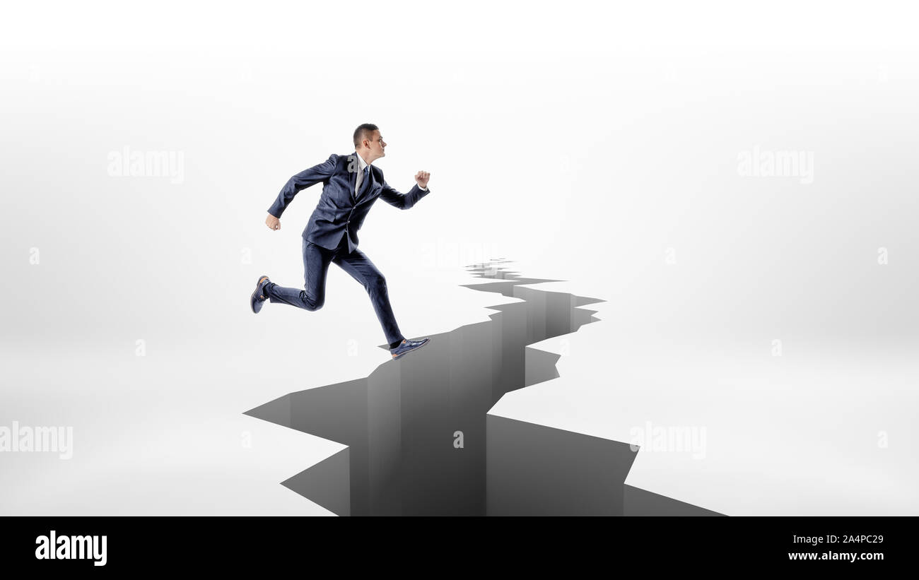 A businessman high-jumps over a long jagged earthquake rift in the ...