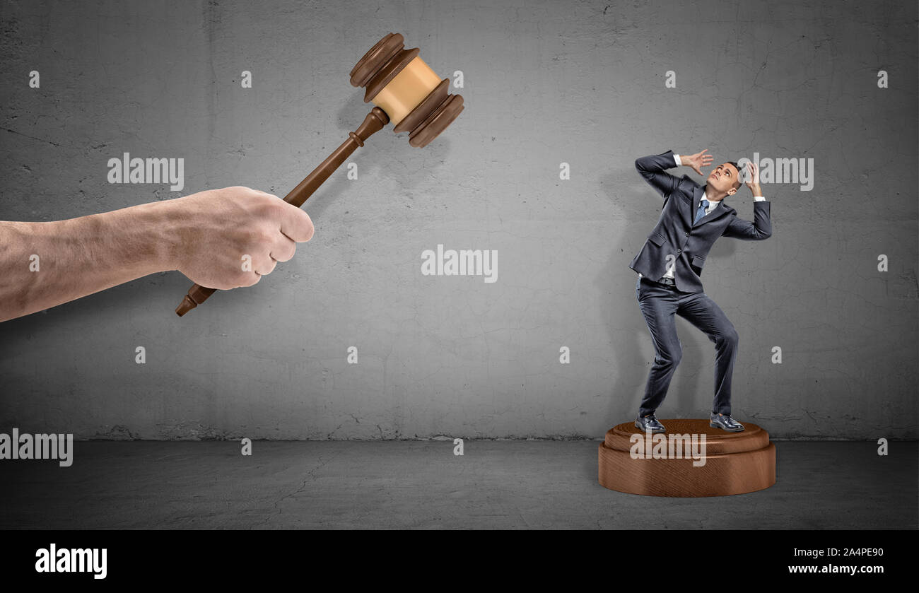 A tiny scared businessman stands on a giant sound block under a large ...