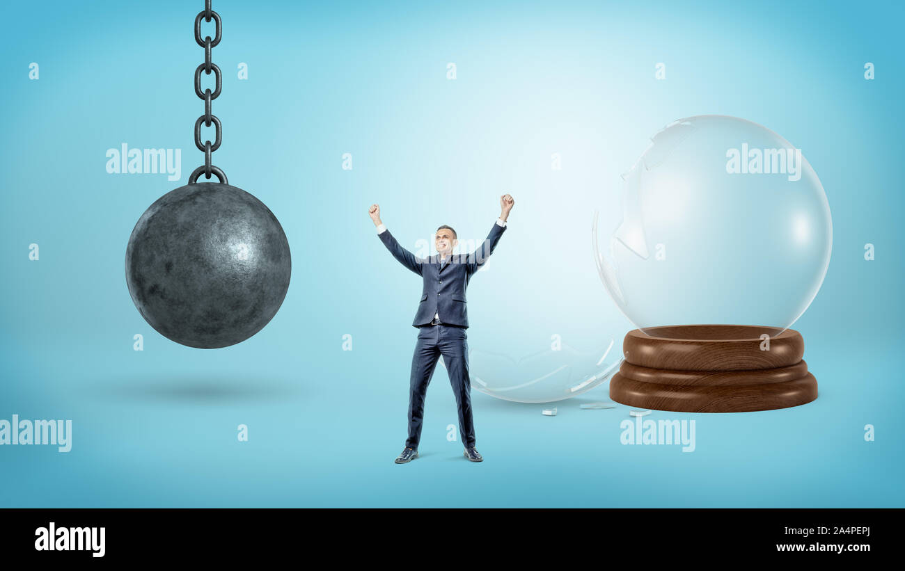 A small victorious businessman stands near a broken glass sphere and an ...