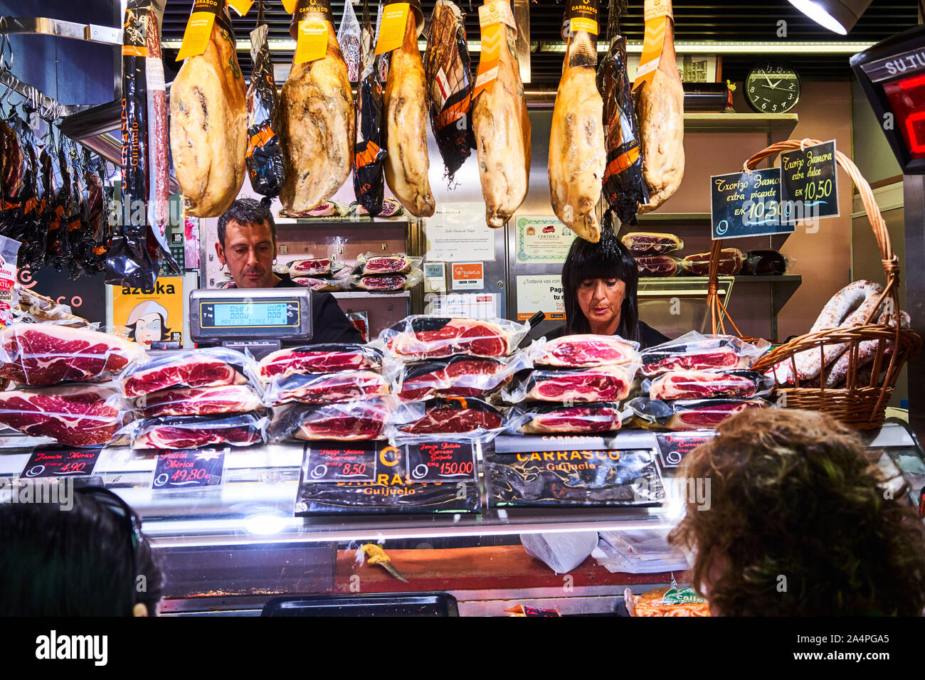 Spanish hams hang from the ceiling of a market stall selling pre ...